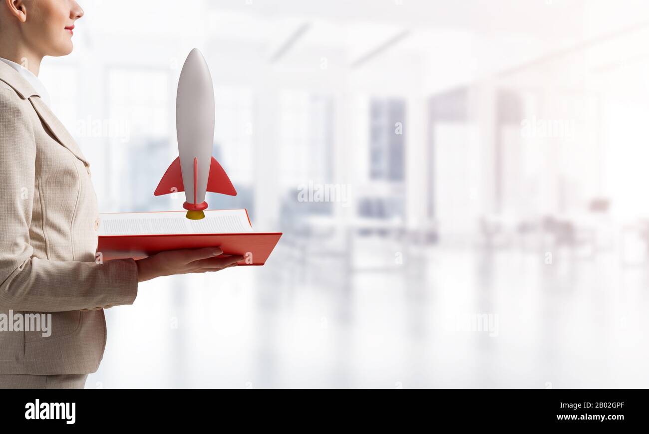 Woman showing rocket ship on open book Stock Photo - Alamy