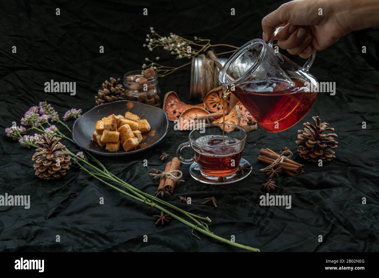 Bael fruit tea is poured from a kettle into glass cup with bark of bael ...