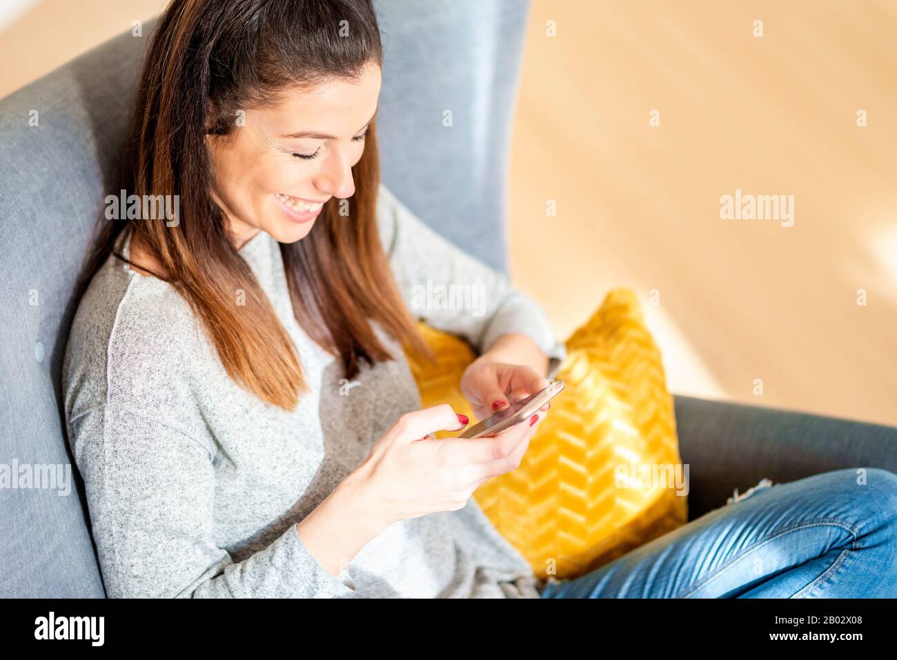 High angle shot of happy woman text messaging while relaxing in the ...