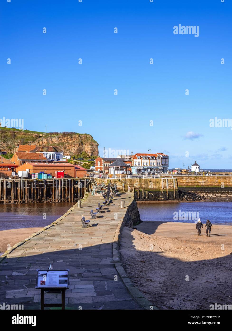 A view of a quay and the pier at Whitby from across the harbour. A ...