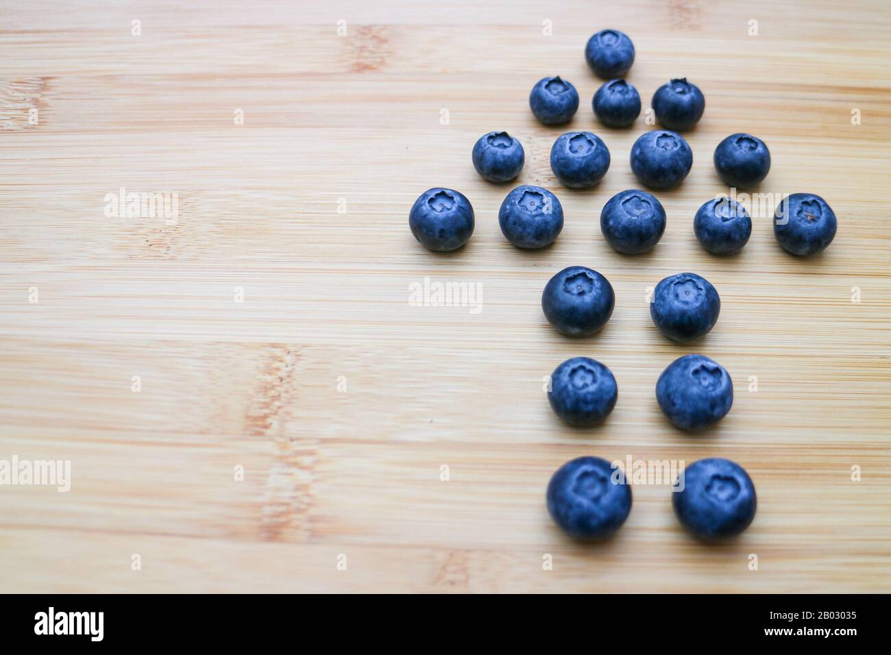 Blueberries arranged geometrically to shape an arrow on a wooden ...
