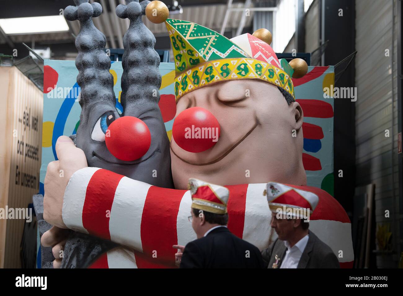 Cologne, Germany. 18th Feb, 2020. Fools walk by a carnival float. The ...