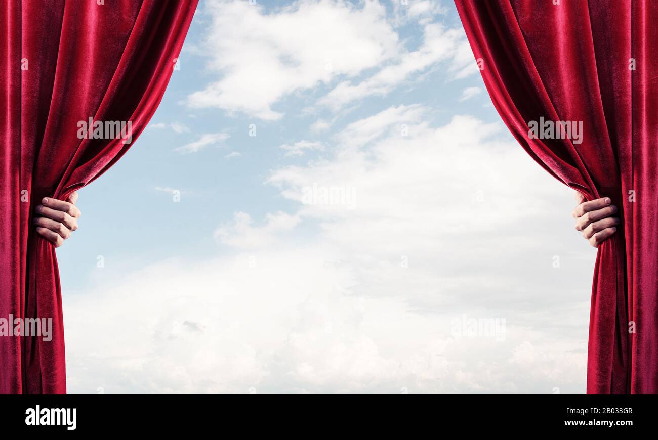 Cloudy landscape behind red curtain and hand holding it Stock Photo - Alamy