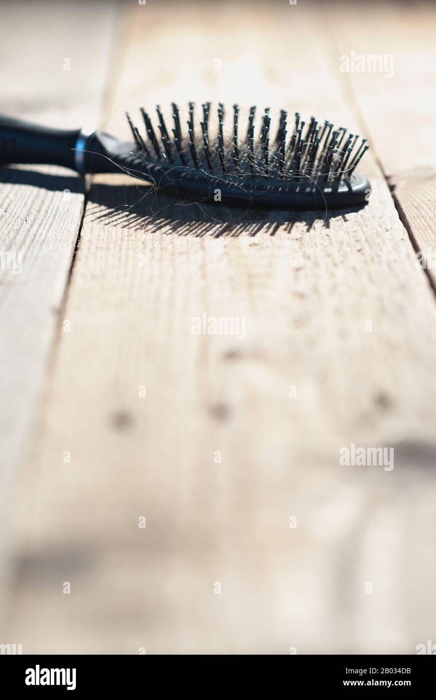 Black comb with blonde hair lies on floorboards Stock Photo - Alamy
