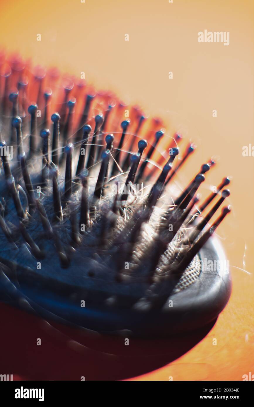 Close-up of black hairbrush with blonde hair on orange floor Stock ...