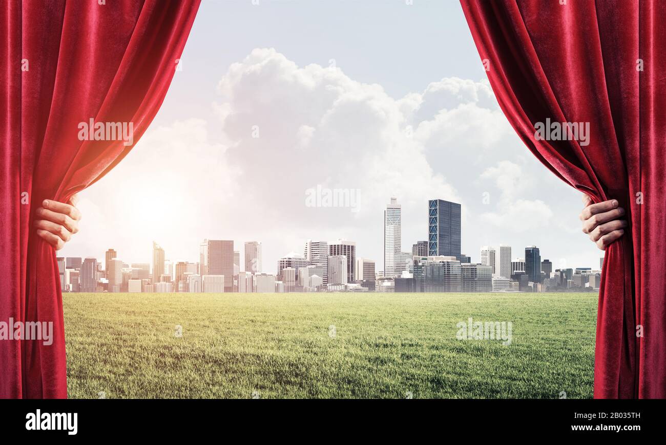 Green meadow behind red curtain and hand holding it Stock Photo - Alamy