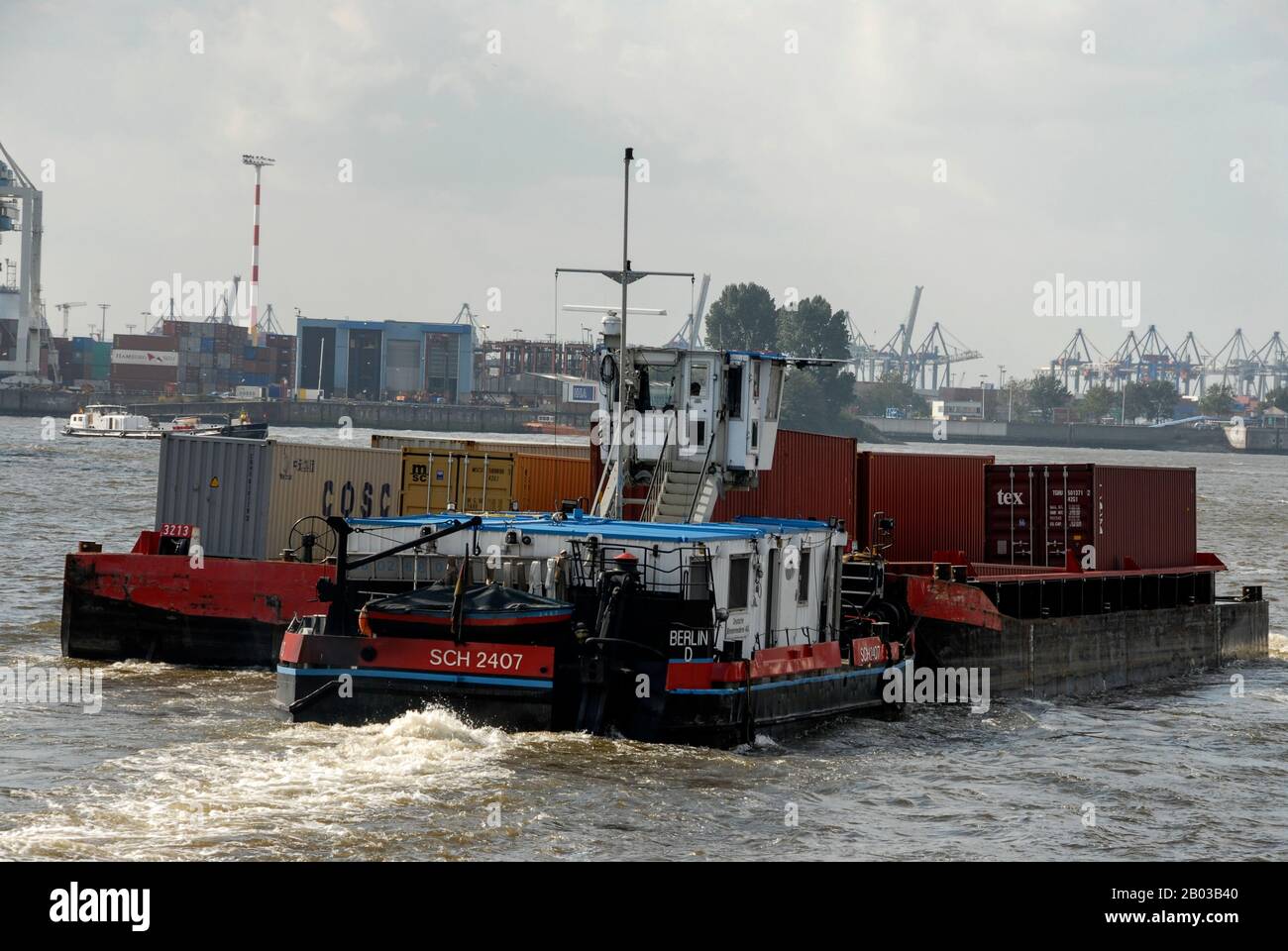 A tugboat pushing a floating platform loaded with containers, heading ...