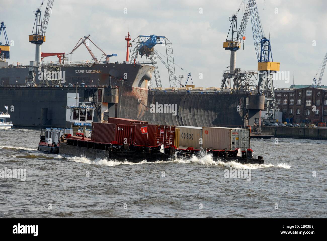A tug pushing a floating platform loaded with containers heading up ...