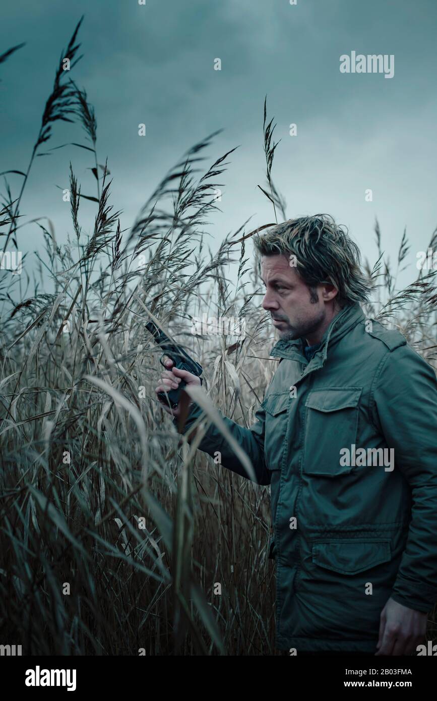 Man with pistol between reed Stock Photo - Alamy