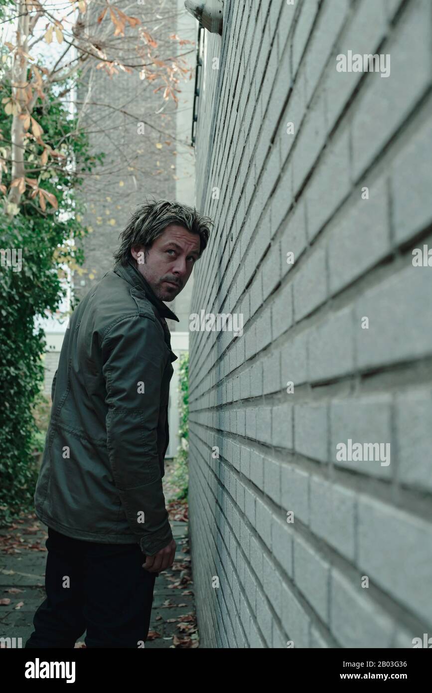 Man looking along white brick wall in alley. Rear view Stock Photo - Alamy