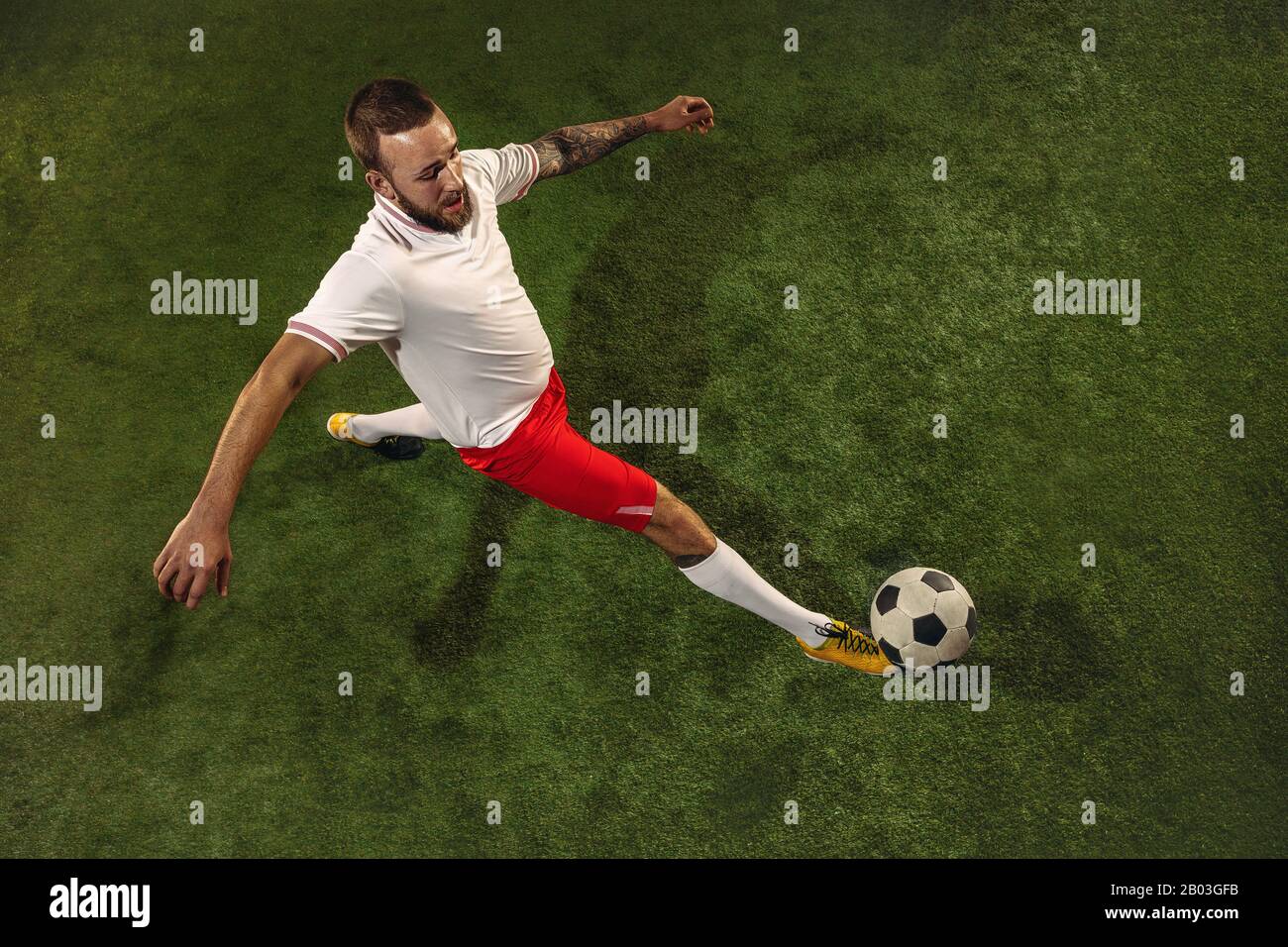 Top view of caucasian football or soccer player on green background of ...