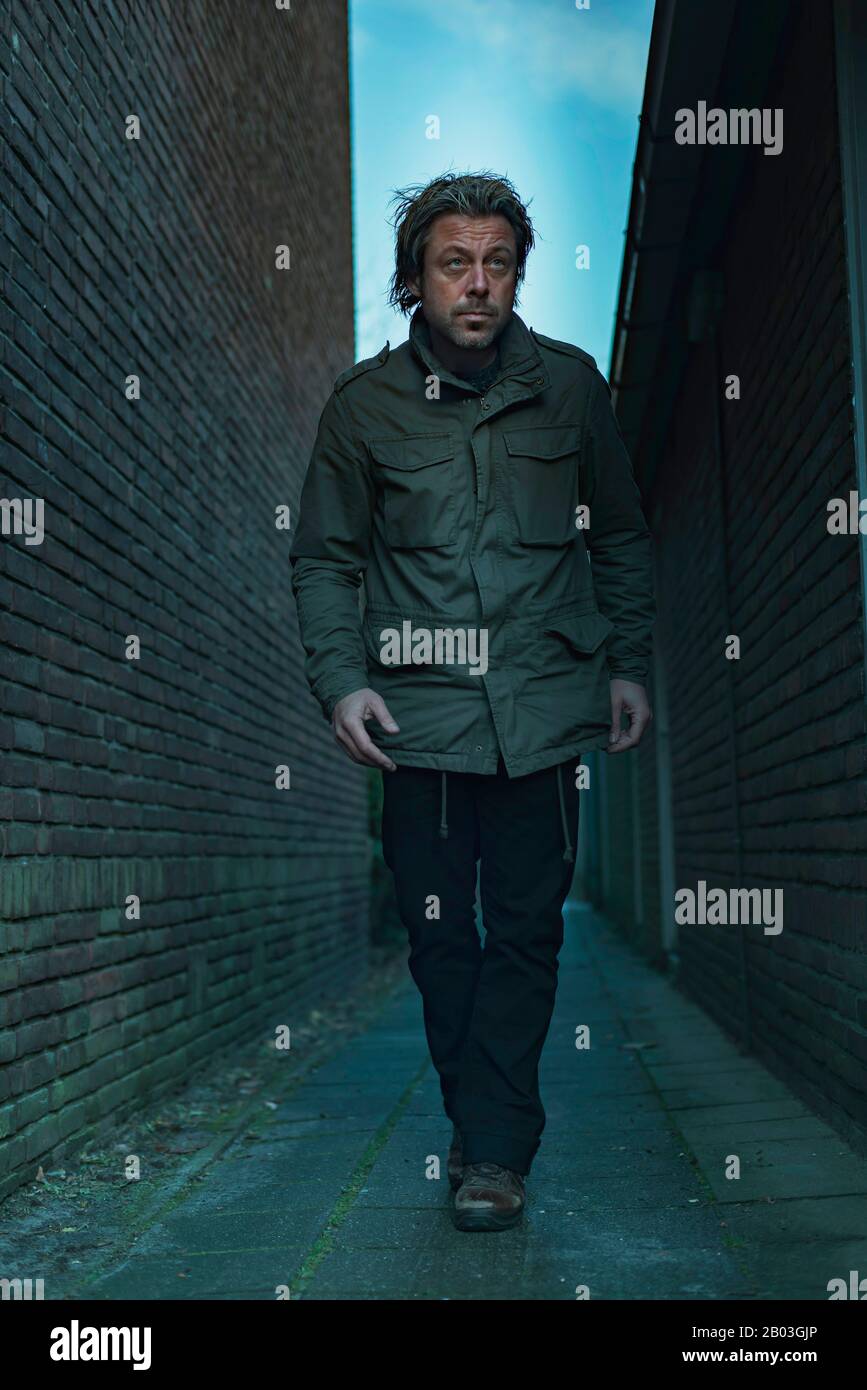 Suspicious man walking in dark urban alley Stock Photo - Alamy