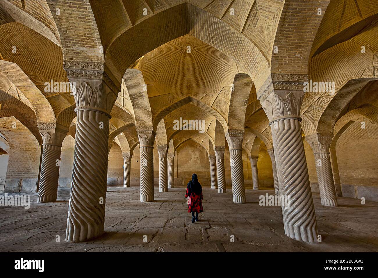 Vakil Mosque with an Iranian woman in red dress under its arches, in ...