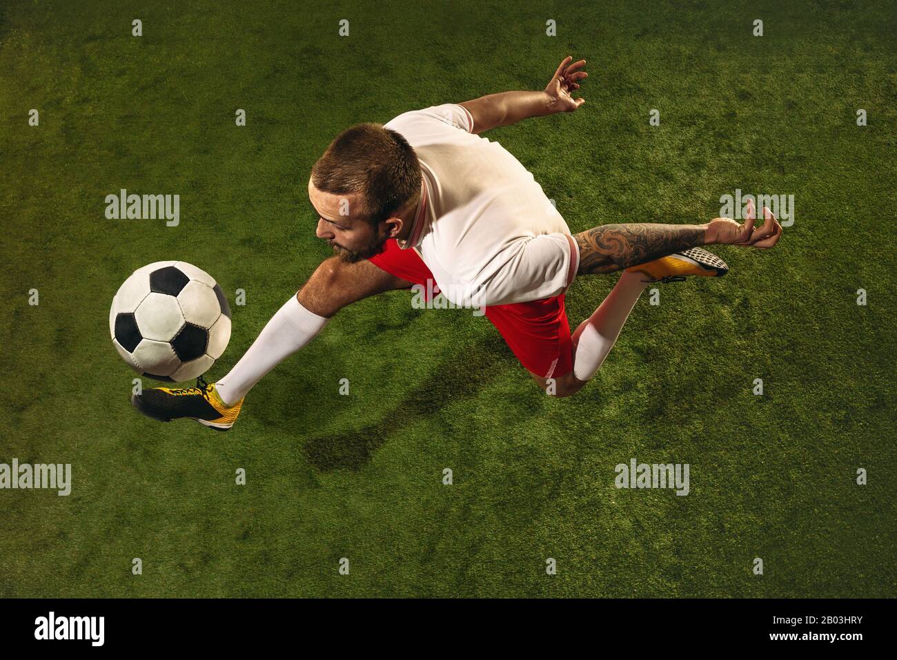 Top view of caucasian football or soccer player on green background of ...