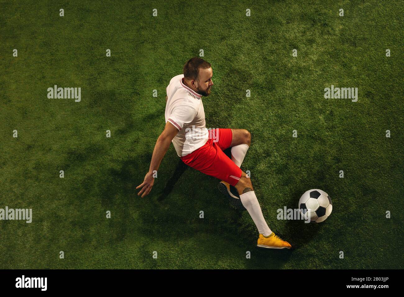 Top view of caucasian football or soccer player on green background of ...