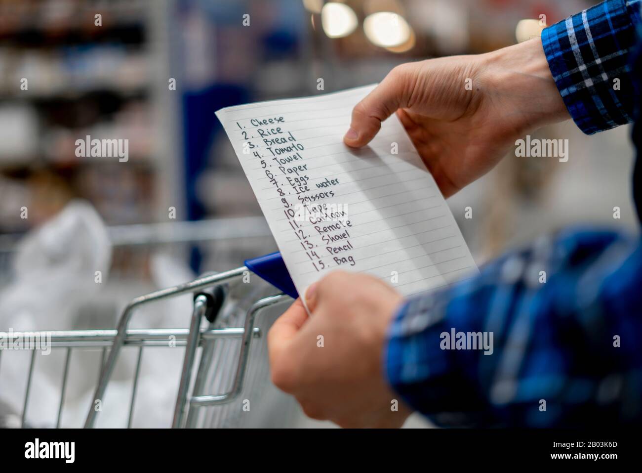 a person's hands holding a shopping list paper sheet and check buying ...