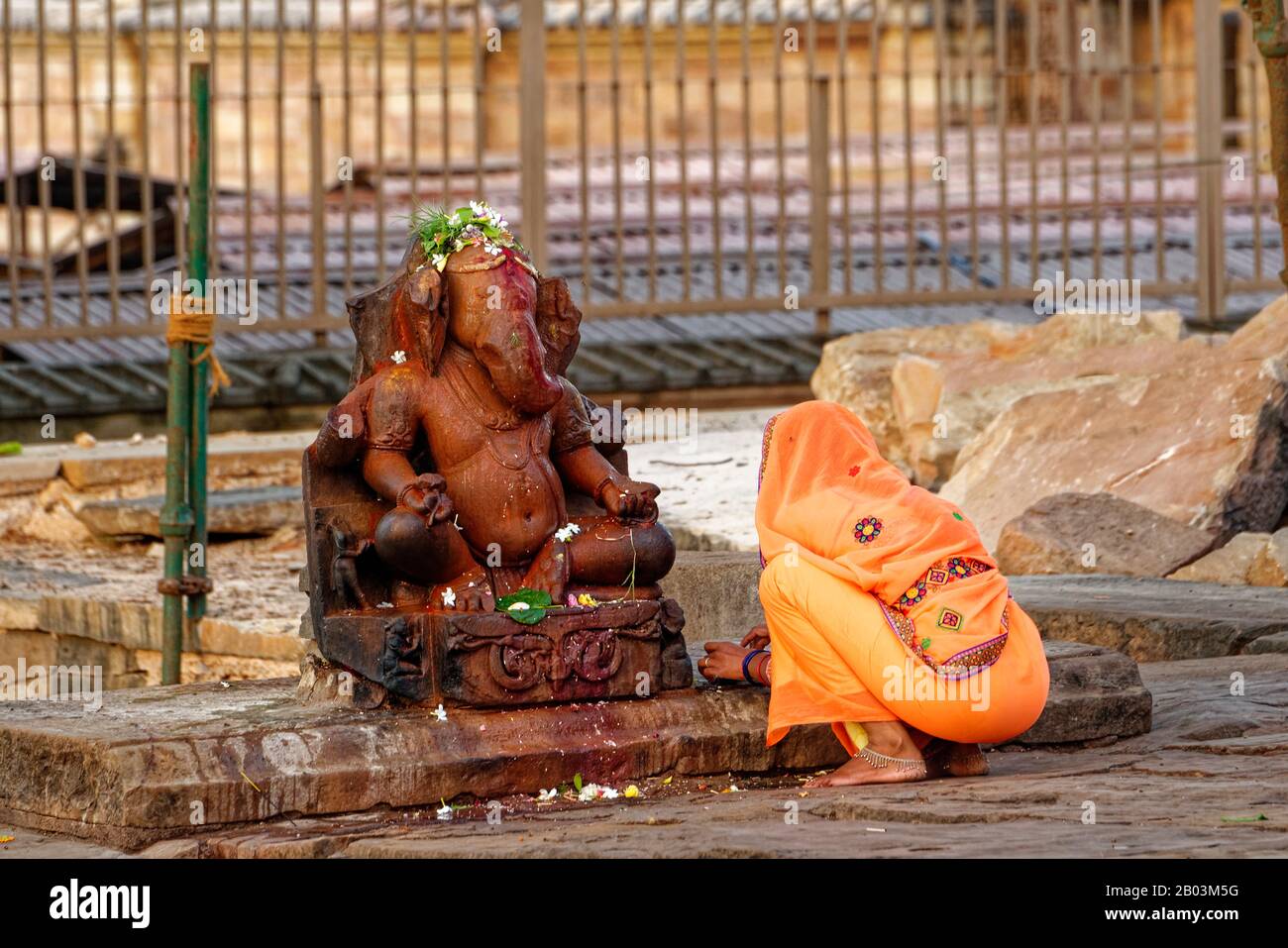 Indian woman crouched in front of a statue of Lord Ganesha, Khajuraho ...