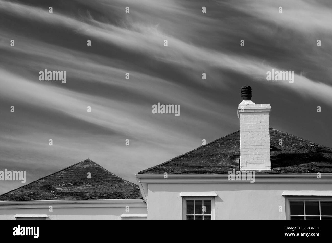 Black and white photo of tiled rooftops, chimney and summery sky with ...