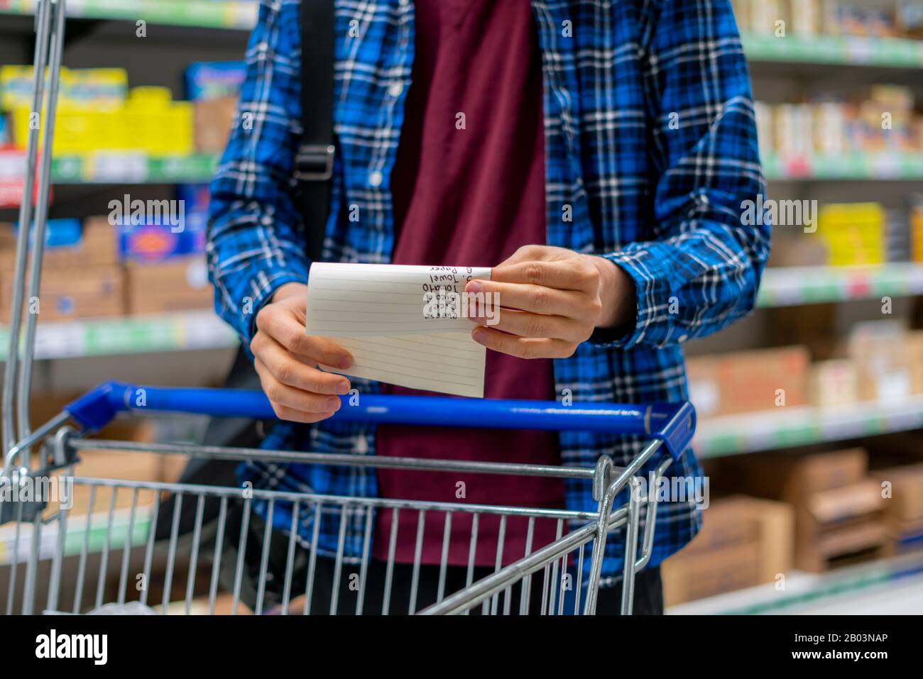 a person's hands holding a shopping list paper sheet and check buying ...