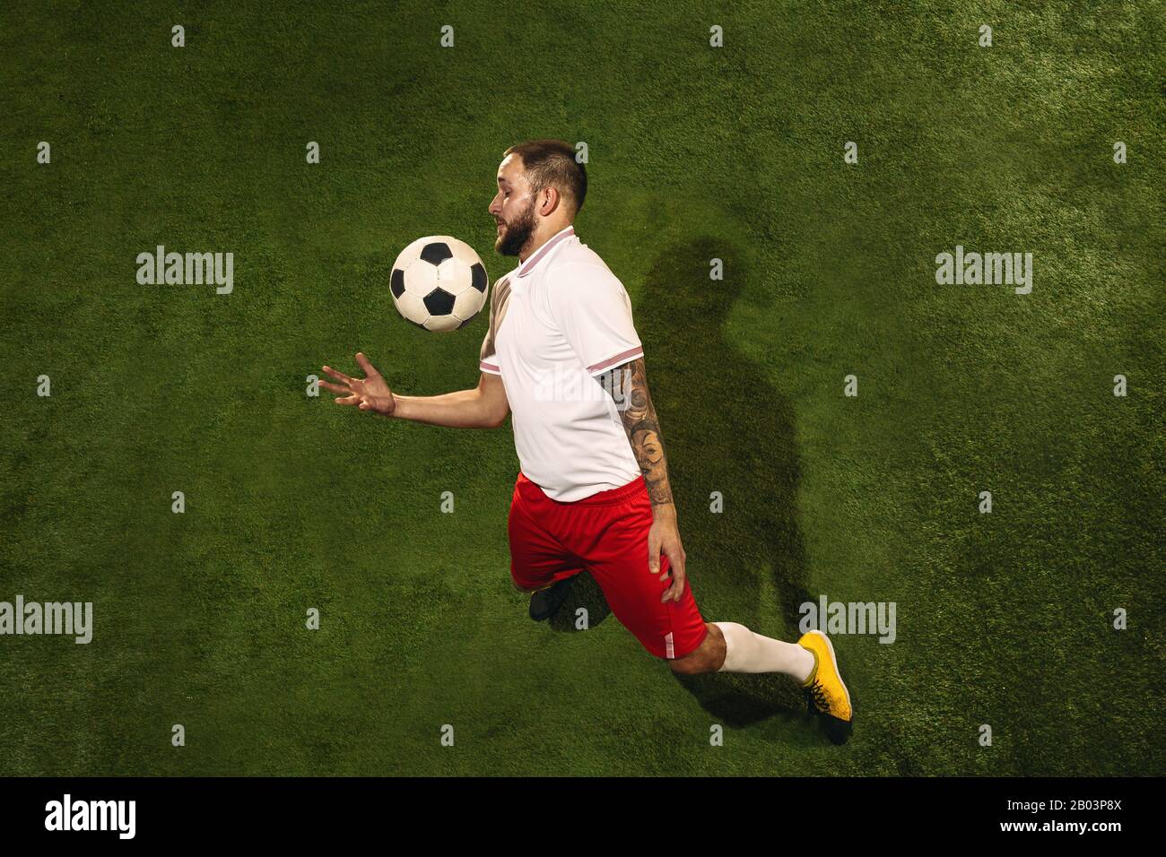 Top view of caucasian football or soccer player on green background of ...