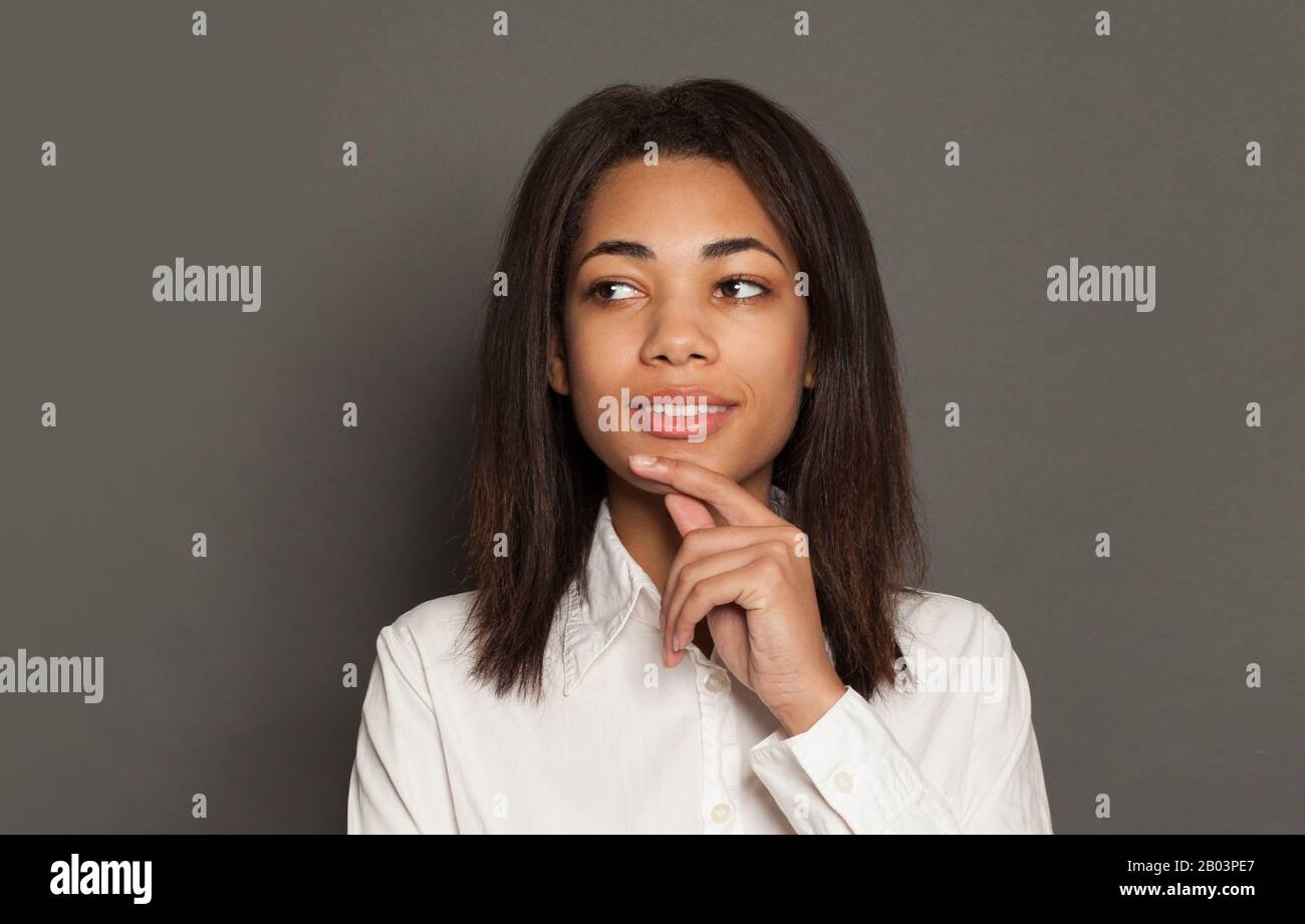 Happy smart black woman brunette thinking on gray background Stock ...