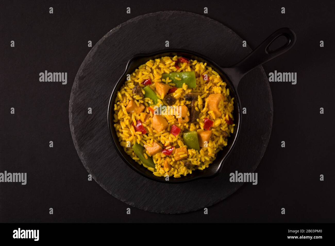 Fried rice with chicken and vegetables on frying iron pan on black ...