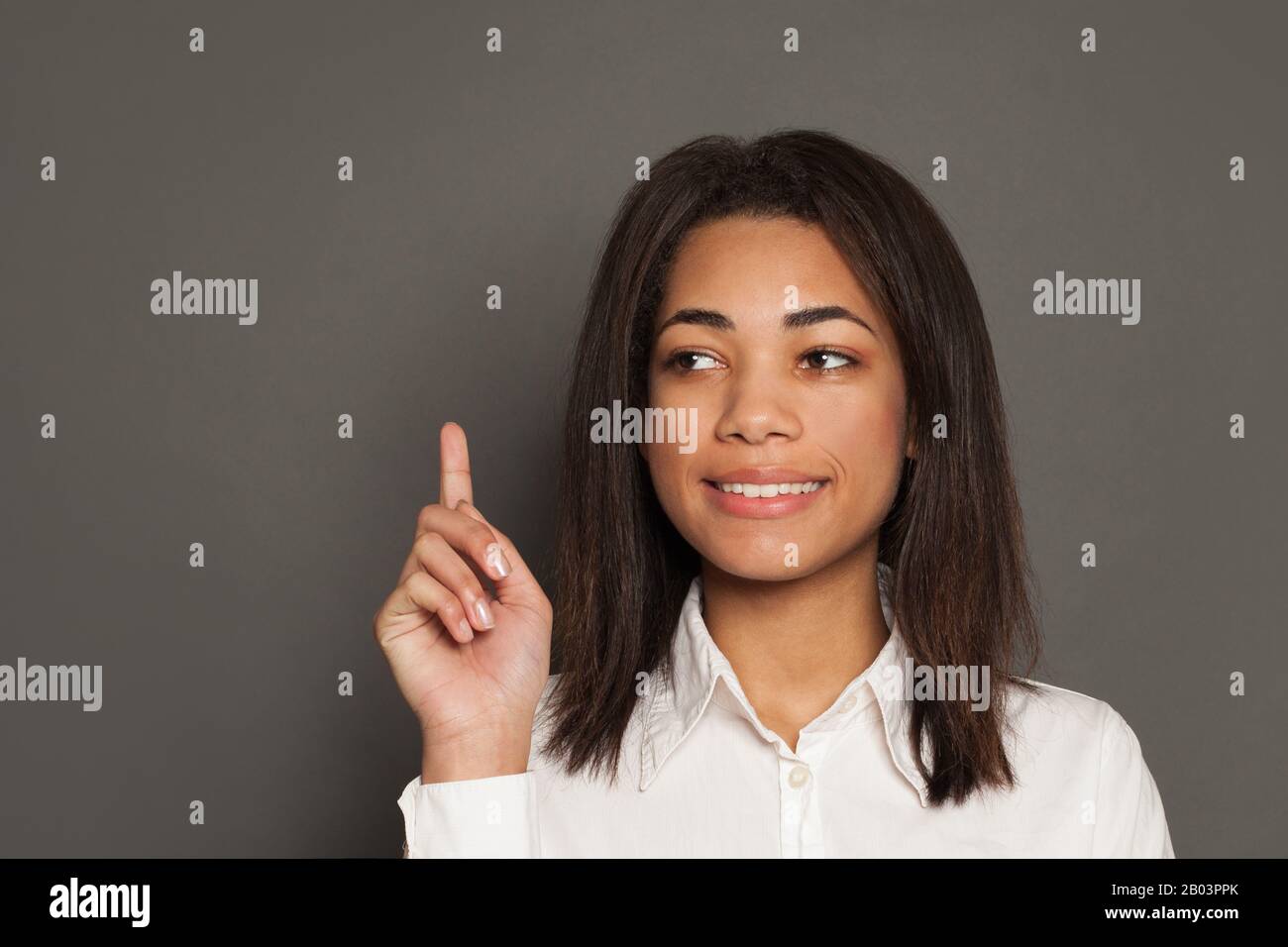 Smart happy student black woman pointing up on gray background Stock ...