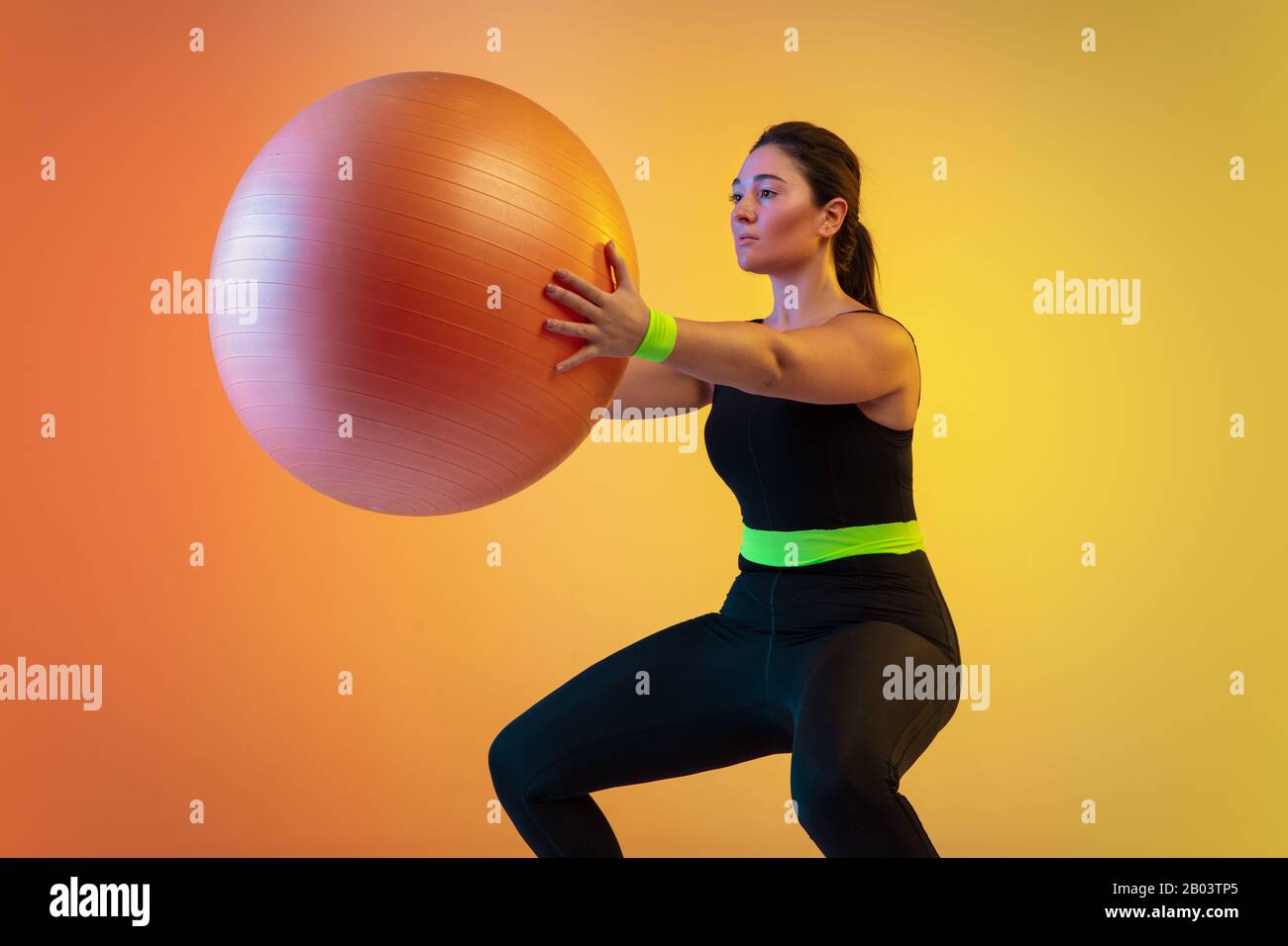 Young caucasian plus size female model's training on gradient orange ...