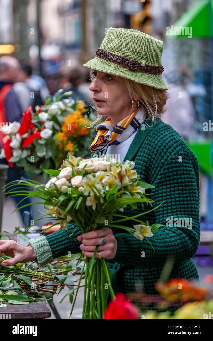 Lady flower selling dressed in green holding a buch of flowers ...