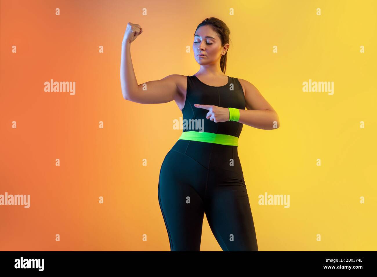 Young caucasian plus size female model's training on gradient orange ...