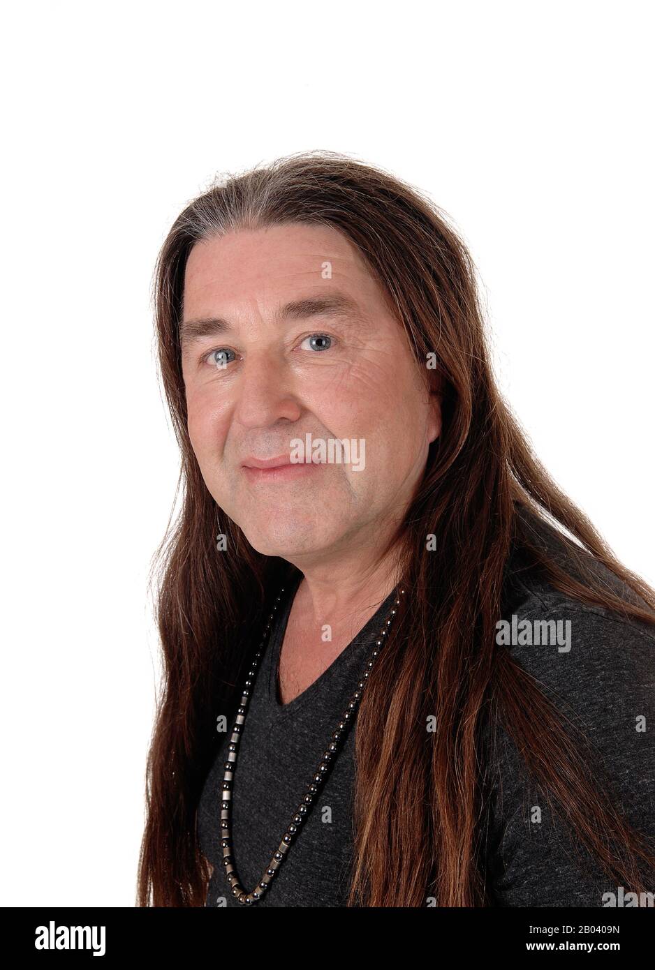 A serious indigenous man sitting for a portrait image with his long ...