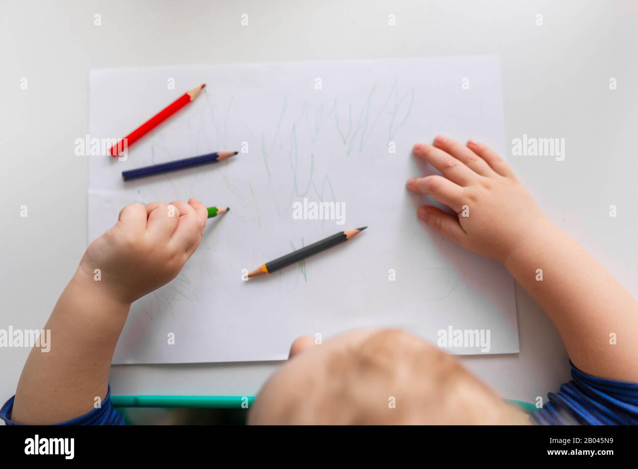 Left handed baby boy drawing a picture with colored pencils Stock Photo ...