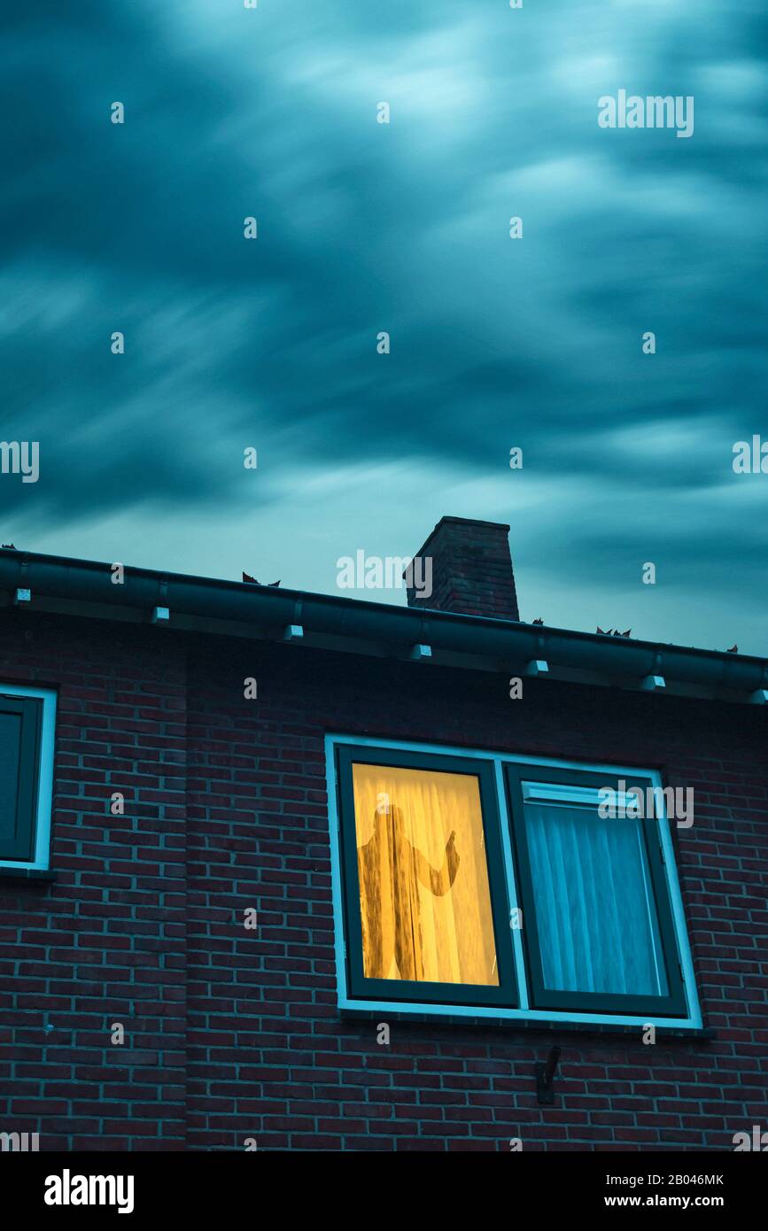 Criminal with pistol in ominous house with illuminated window under ...