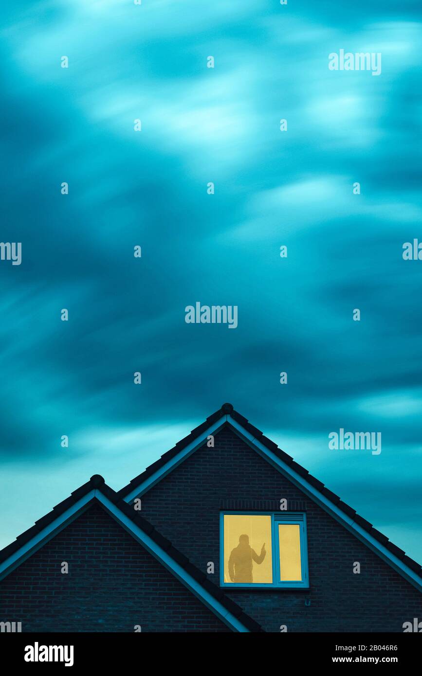 Criminal with pistol in ominous house with illuminated window under ...