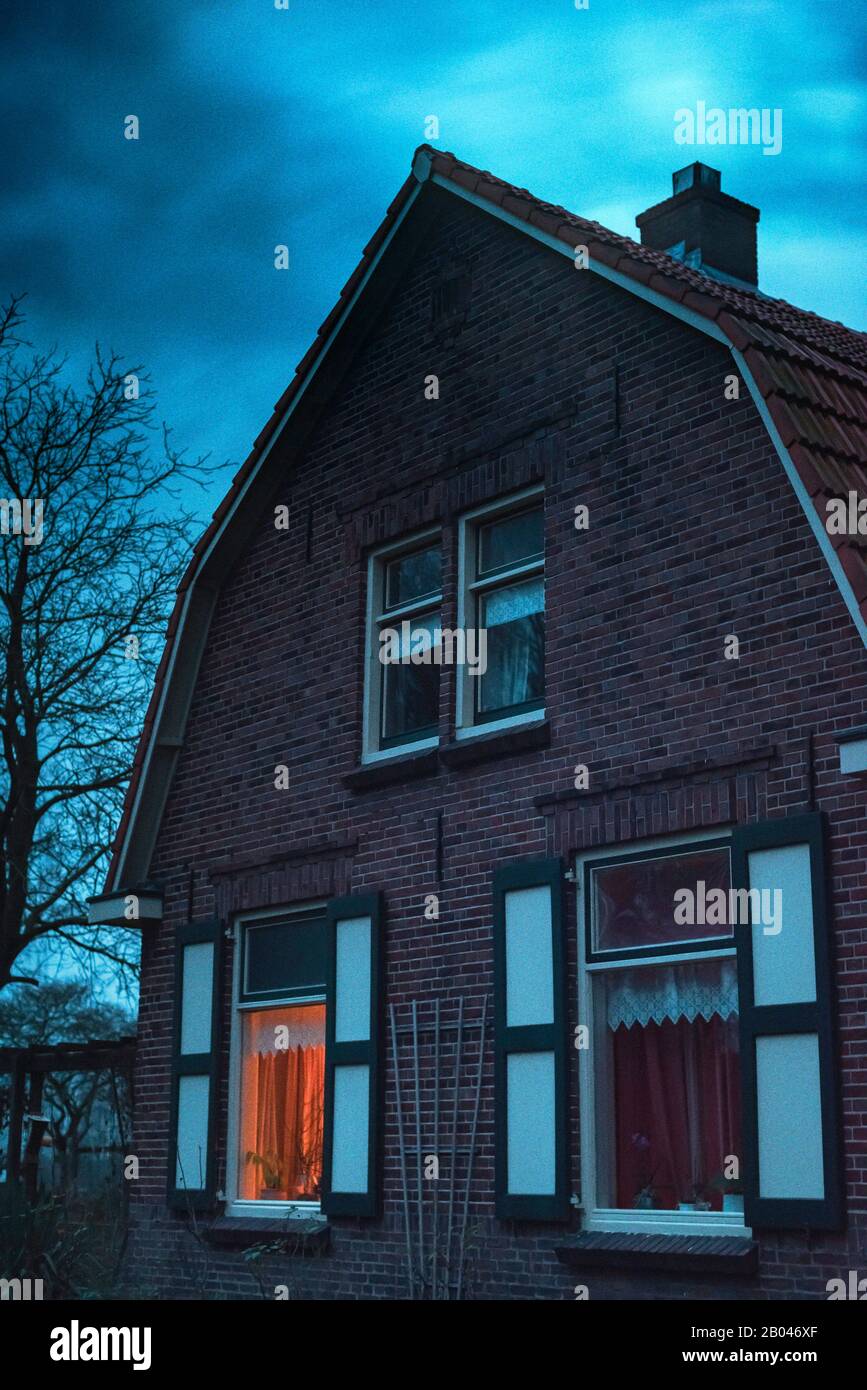 Ominous house with illuminated window under stormy sky at twilight ...