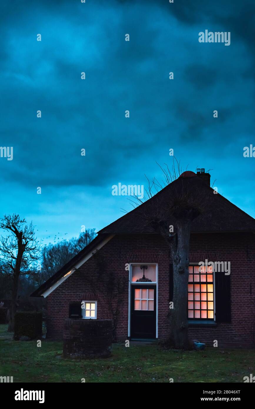 Creepy house with illuminated windows under stormy sky at twilight ...