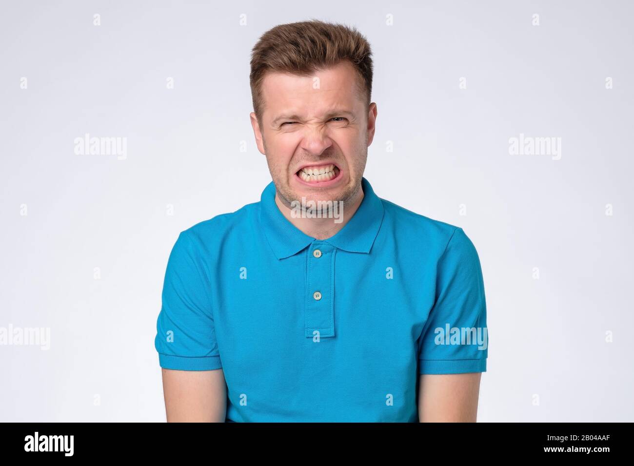 Young angry man is about to lose his temper on gray background ...