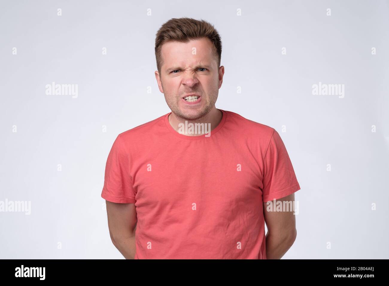 Young angry man is about to lose his temper on gray background ...