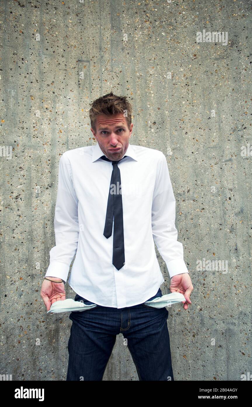 Man in shirt and tie pulling out his empty pockets to show his poverty ...