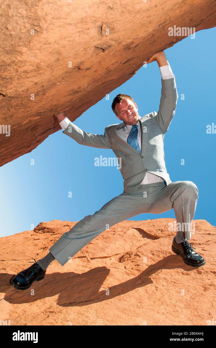 Strong office worker straining to lift massive rock outdoors Stock ...