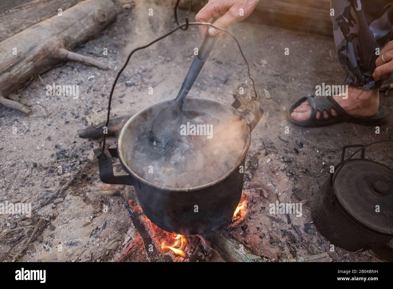 Cooking on fire. Man Cook Some Food in Bowler Camp Stock Photo - Alamy
