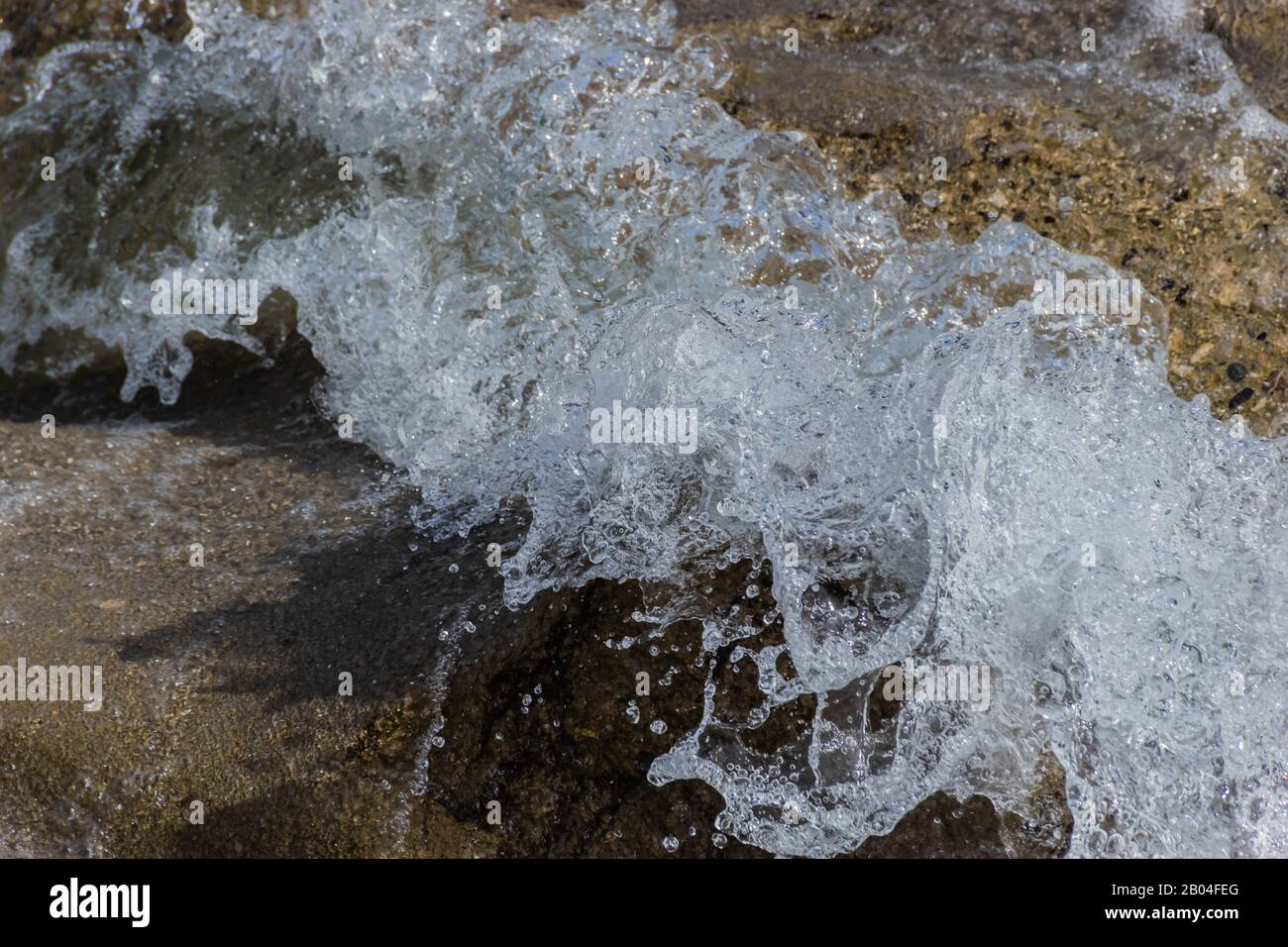 A close-up of a wave splashing over the mountain river cascade boulders ...