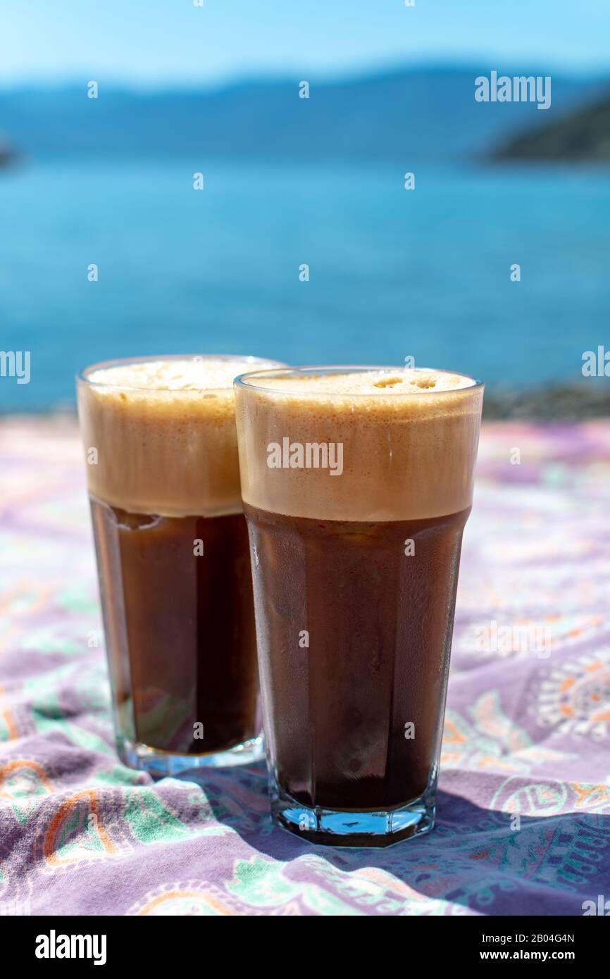 Two glasses of greek cold iced instant coffee with foam frappe on sunny ...