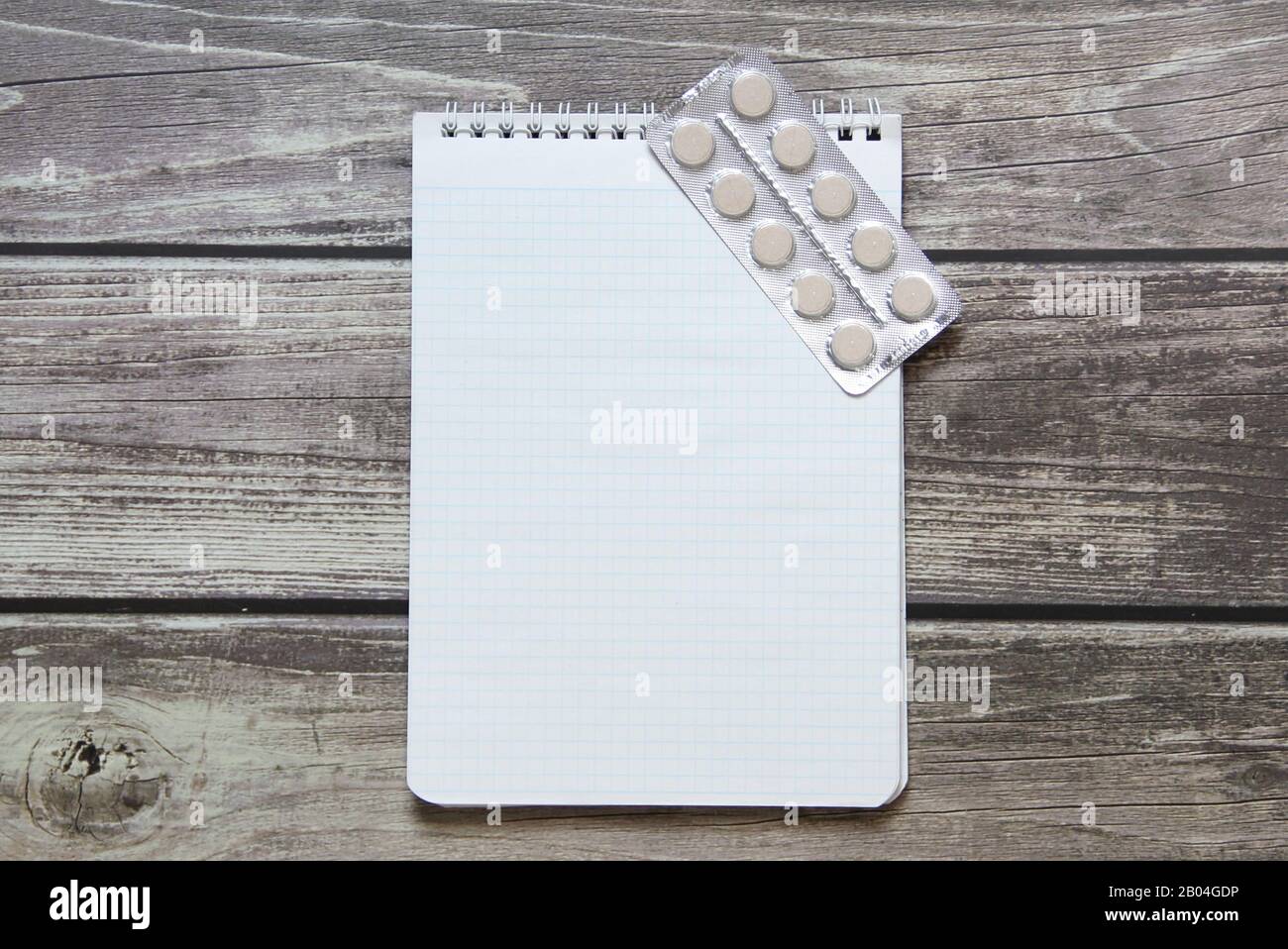 Notepad with a blank white sheet in a checker paper with pills in a ...