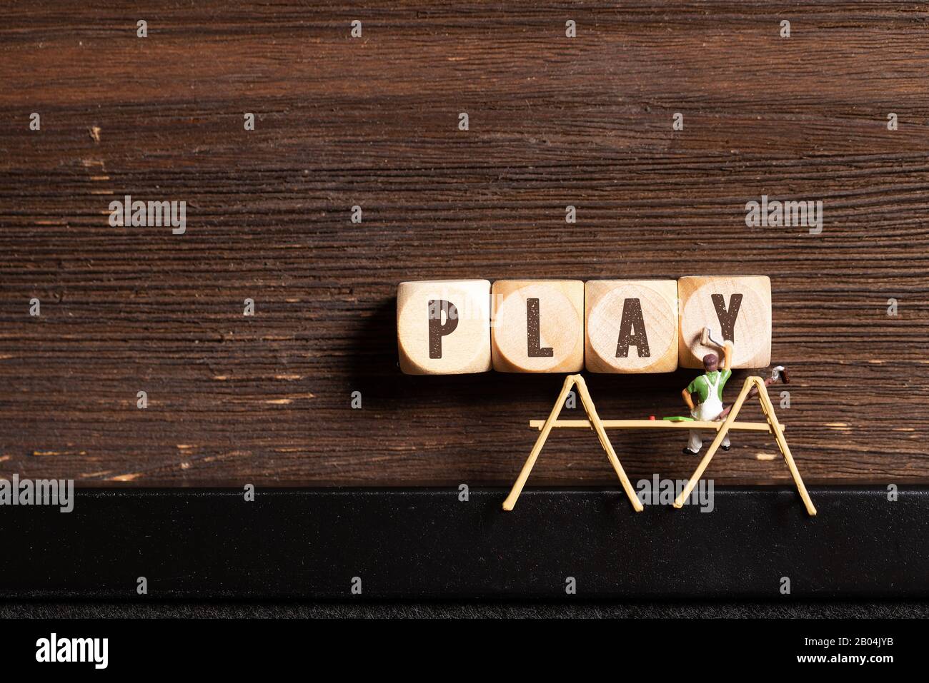 wooden blocks with and a painter figure writing PLAY on them on wooden ...