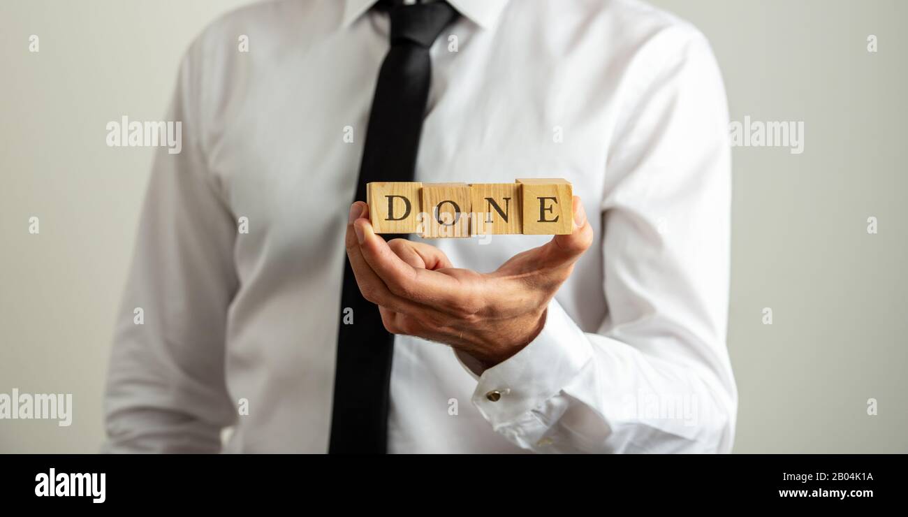 Successful businessman holding a Done sign spelled on wooden cubes in a ...