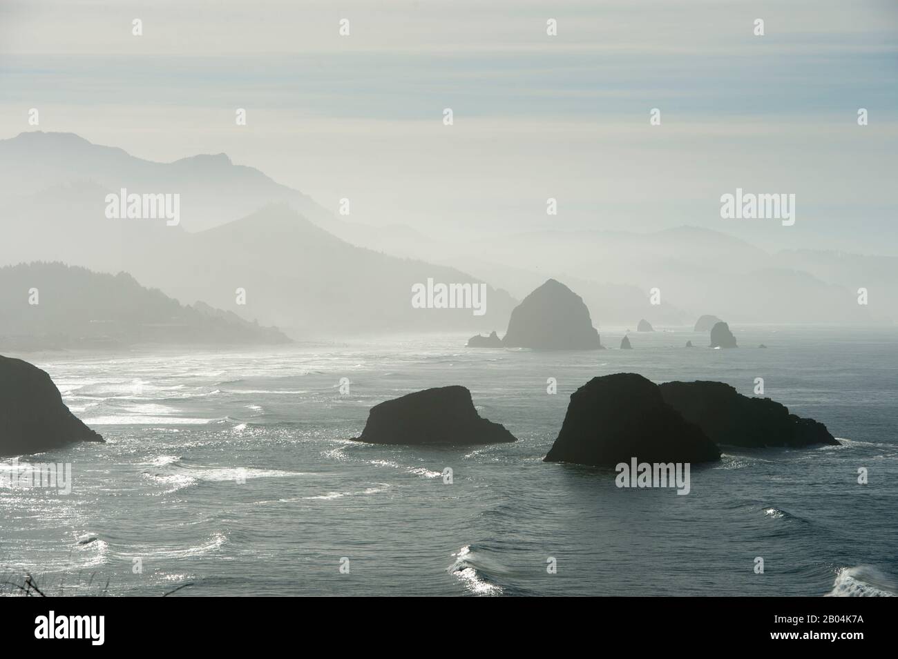 View of backlit Haystack Rock and sea stacks from Ecola State Park ...