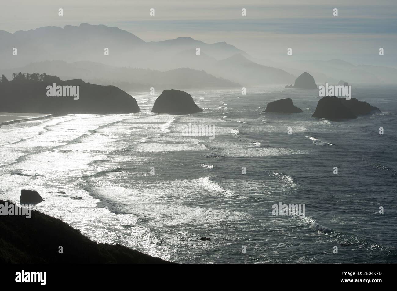 View of backlit Haystack Rock and sea stacks from Ecola State Park ...