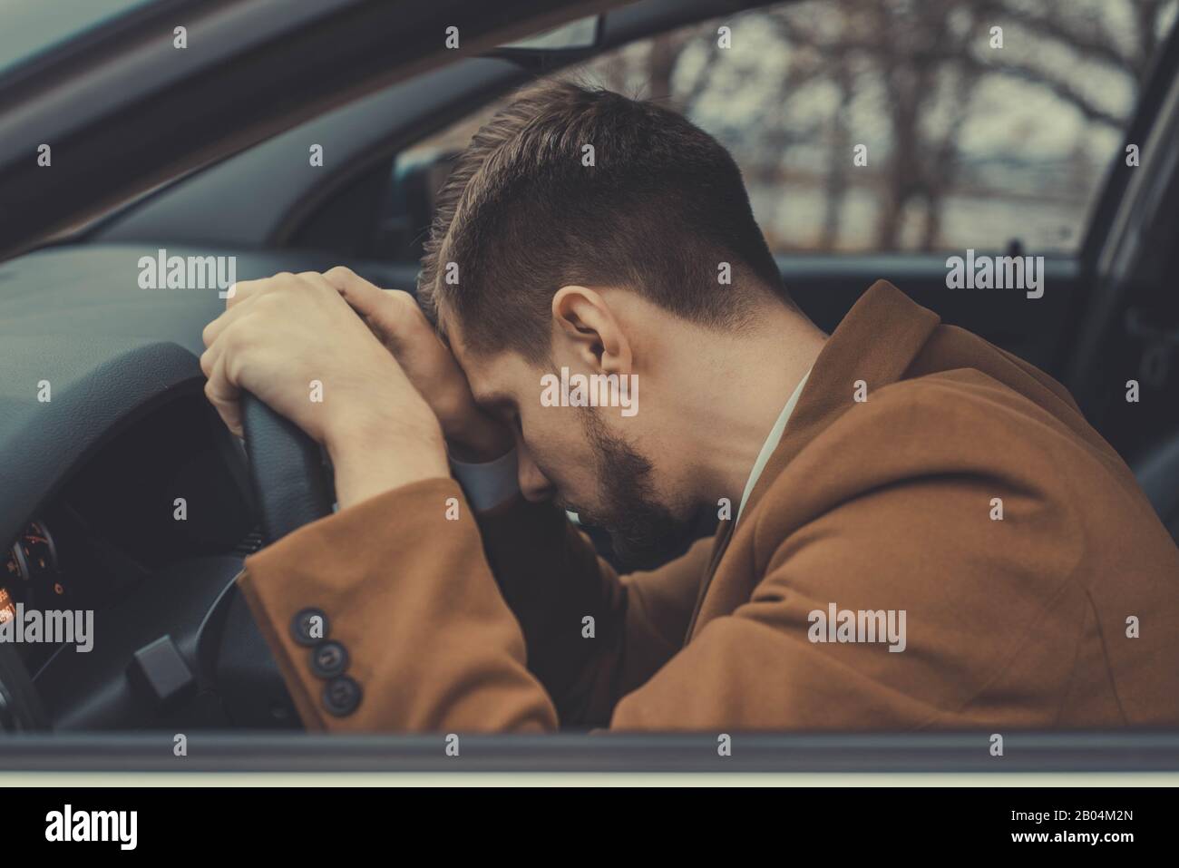 a young man of thirty years, holding his head, having a headache ...