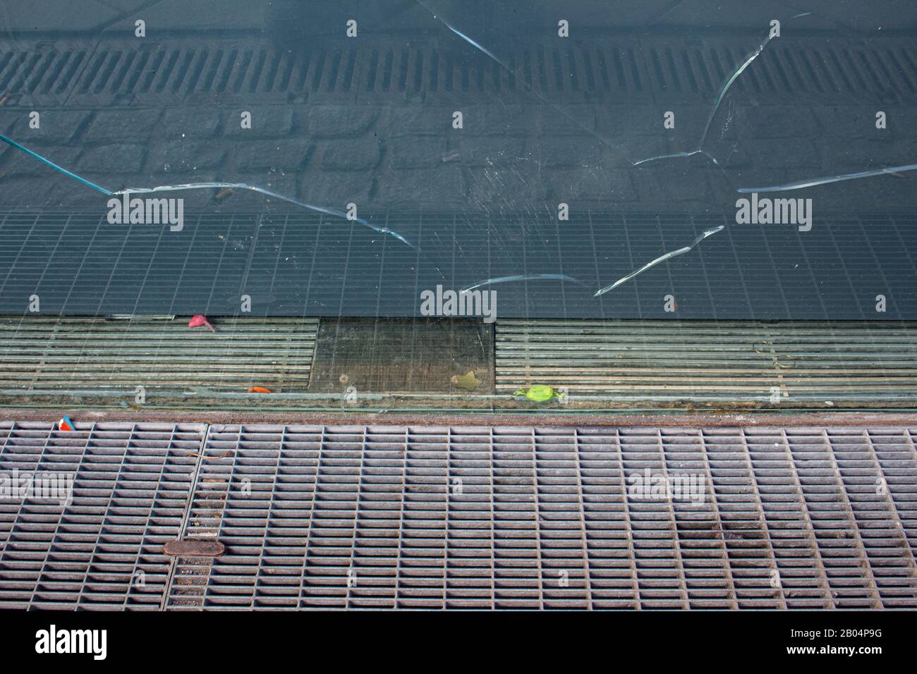 Crack in a broken store window and a reflection of a metal grille Stock ...